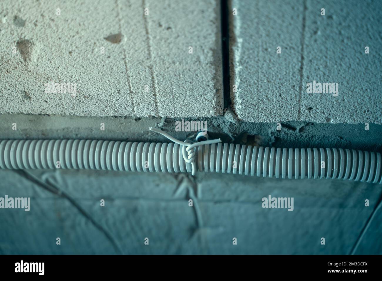Graues pvc-Wellrohr mit elektrischen Drähten, die an der Wandnaht ...