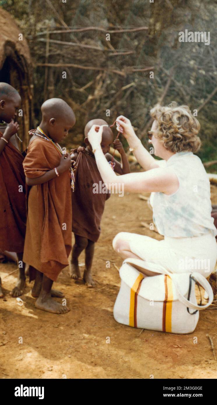 Touristin schenkt einem Massaikind eine Kette in Arusha, Tansania um 1982. Touristinnen, die ...