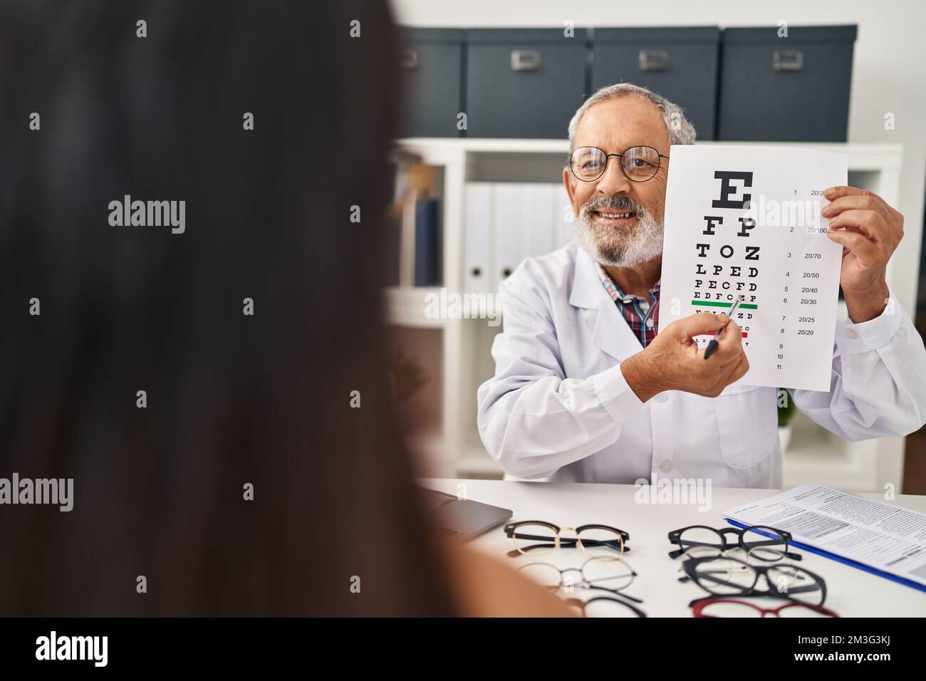 Leitender grauhaariger Mann-Optiker, der einen Snellen-Augentest an ...