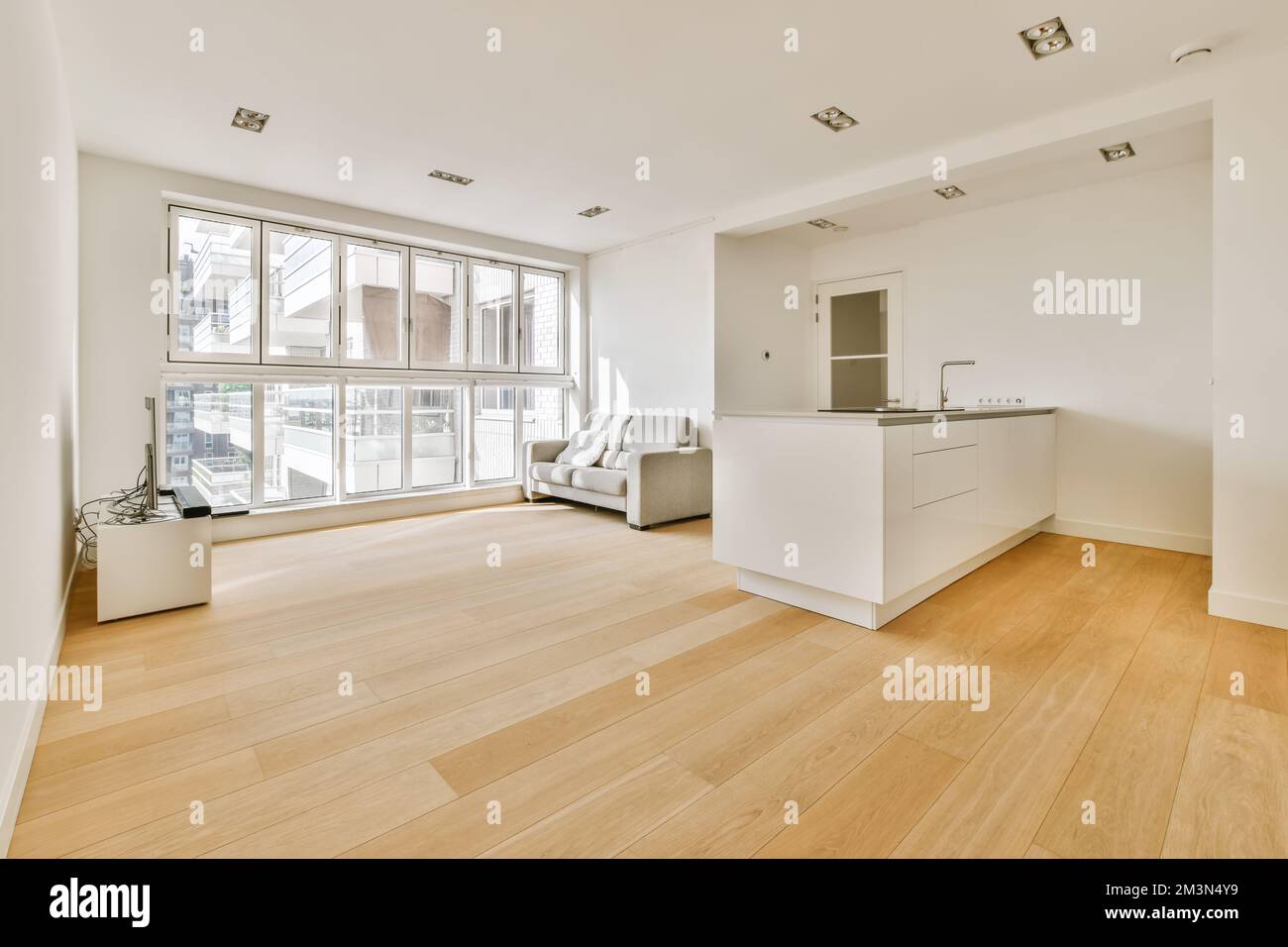 Ein leeres Wohnzimmer mit Holzfußboden und weißen Wänden auf der rechten Seite des Zimmers ist ...