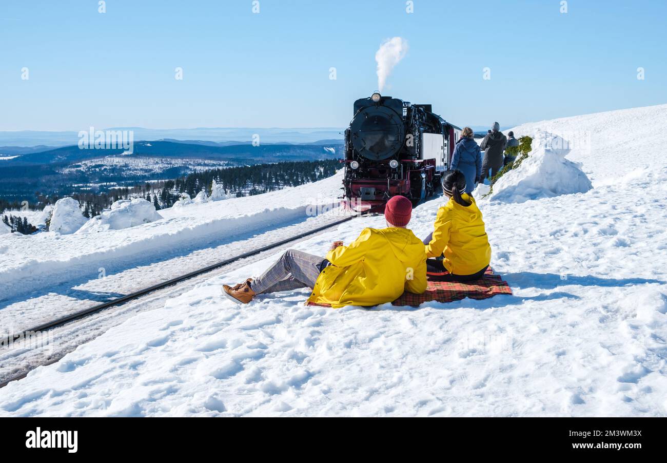 Ein paar Männer und Frauen beobachten die Dampfeisenbahn im Winter im ...