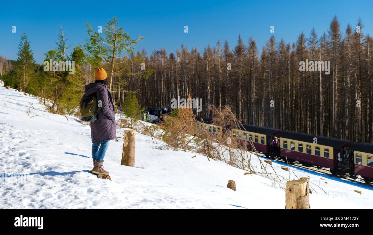 Frauen, die im Winter im Schnee den Dampfeisenbahn im Harz-Nationalpark ...