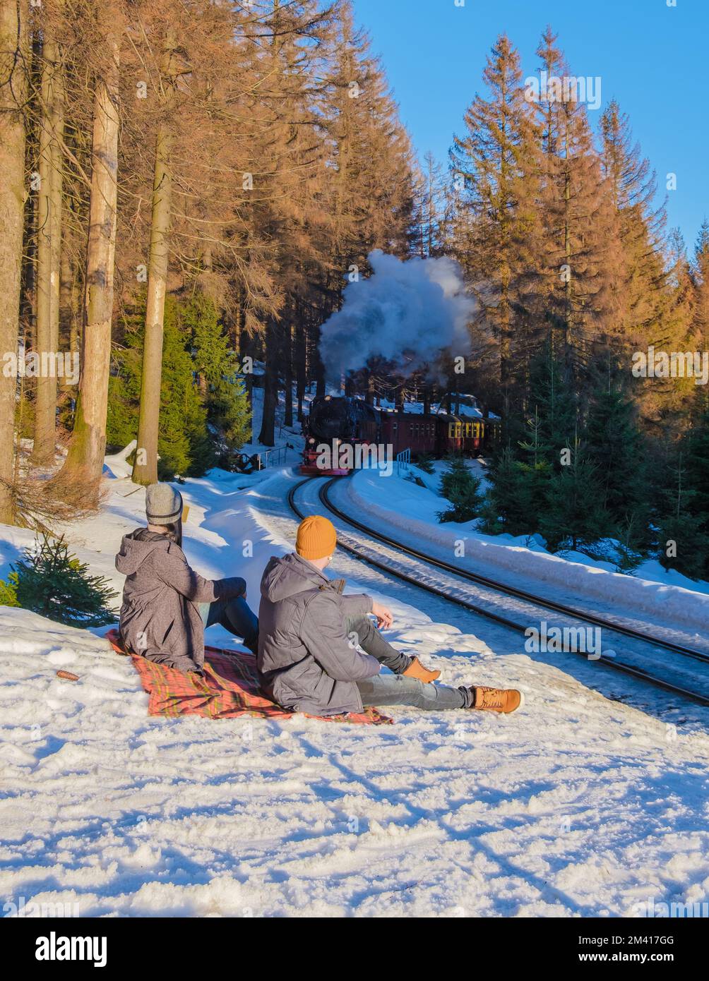Ein paar Männer und Frauen beobachten die Dampfeisenbahn im Winter im ...