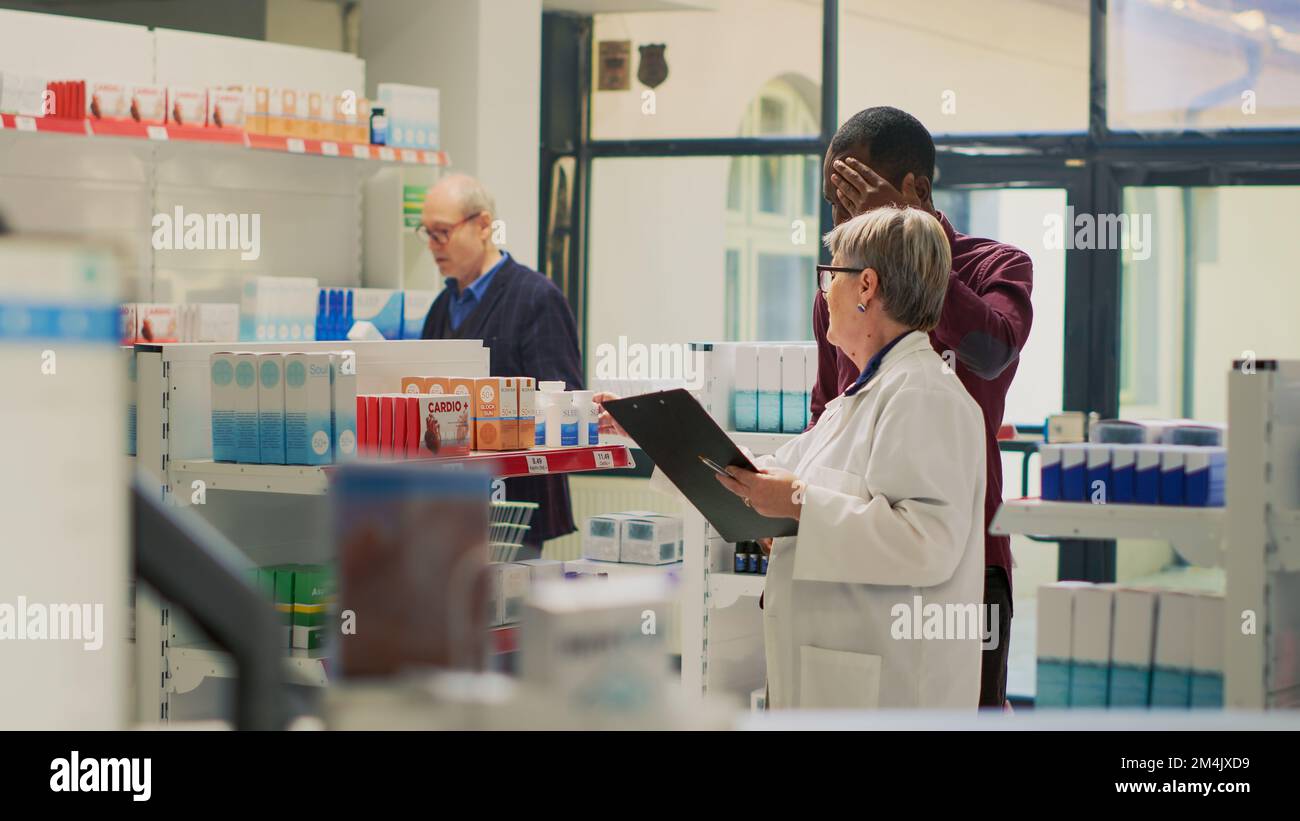 Junger männlicher Kunde mit Kopfschmerzen im Apotheke-Einzelhandel, der ...