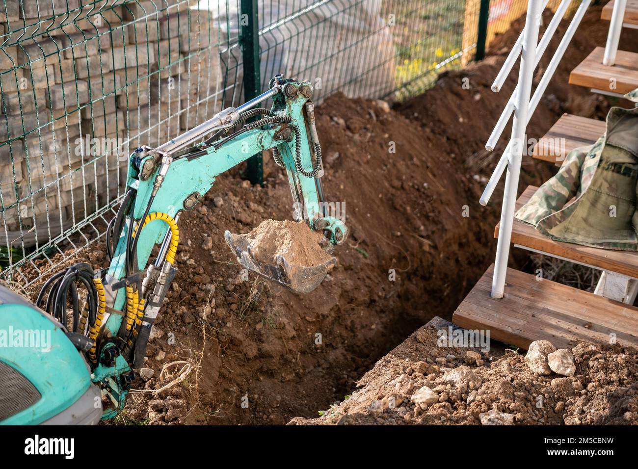 Minibagger gräbt einen Graben, um Rohre zu verlegen. Nahaufnahme eines ...