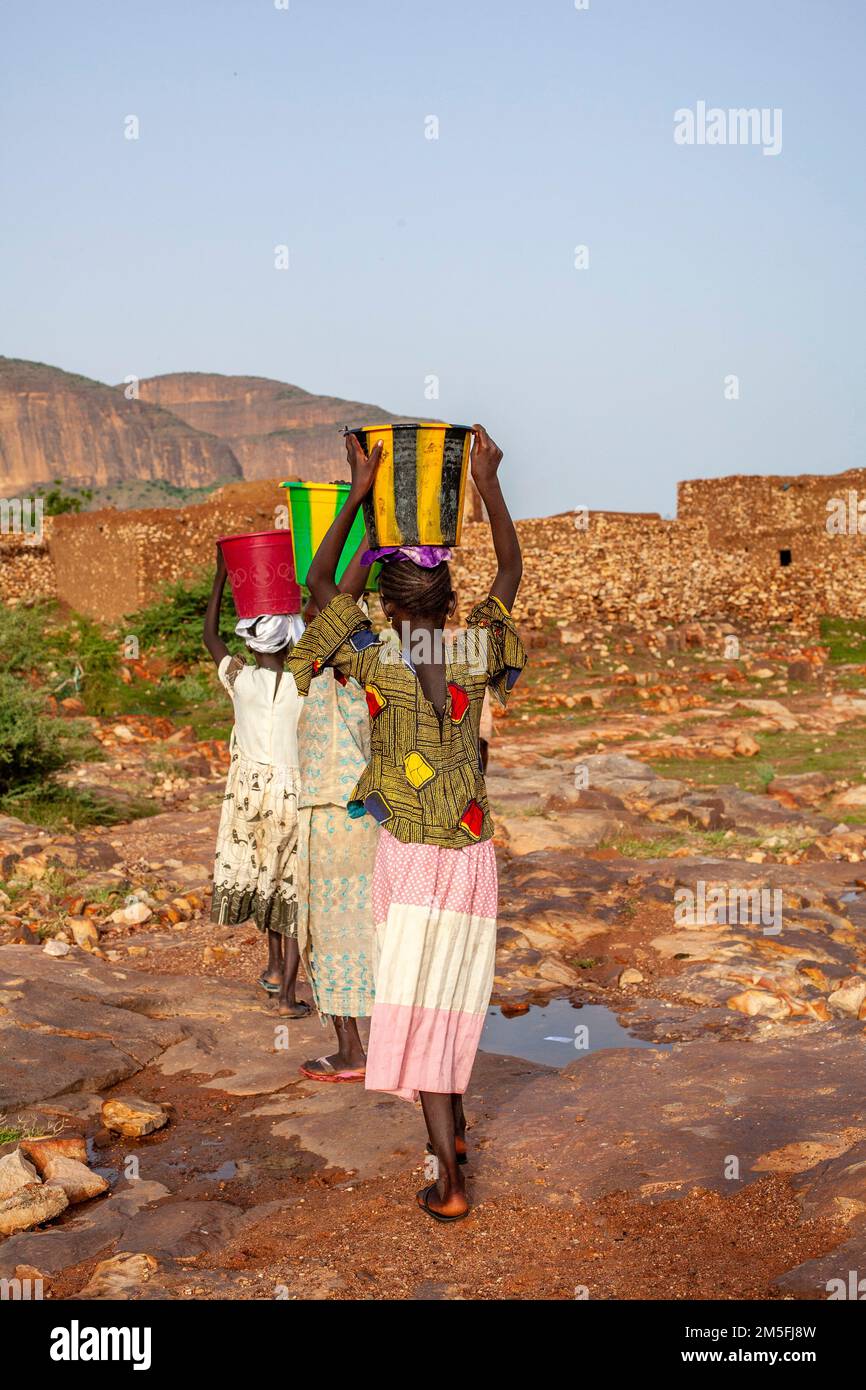 Zwei afrikanische Kinder, die Wasser zu ihrem Haus transportieren ...