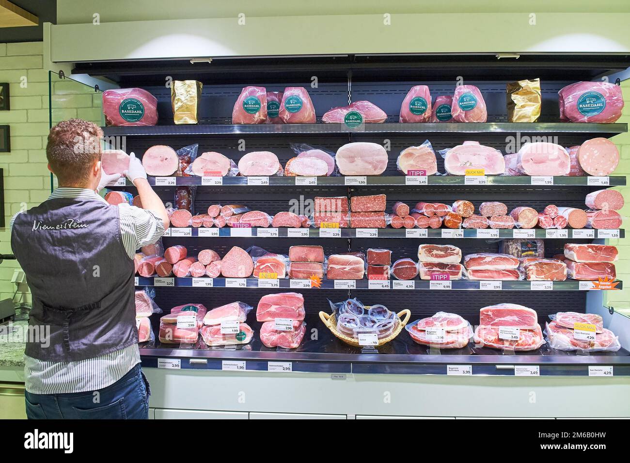 Mitarbeiter beim Sortieren von Waren im Wurst- und Fleischwarenregal ...