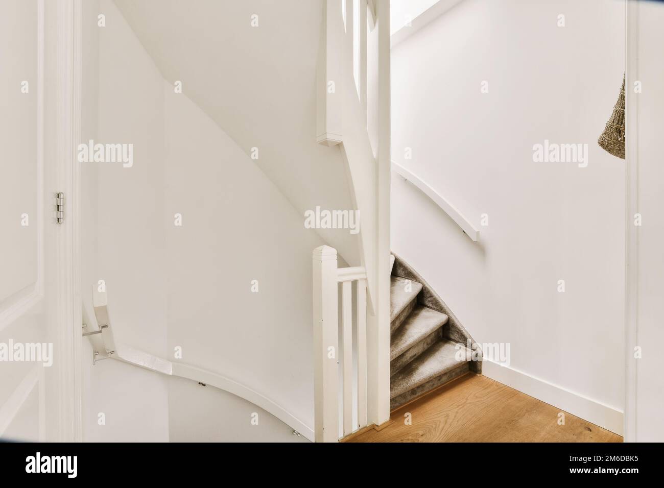 Eine Treppe in einem Haus mit weißen Wänden und Holzfußboden die ...