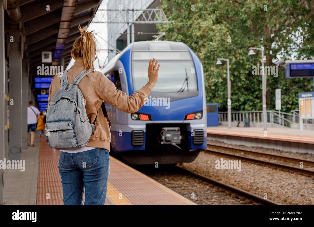 Junge Frau auf dem Bahnsteig, die auf den Zug wartet. Hübsches Mädchen am Bahnhof. Fahren Sie ...