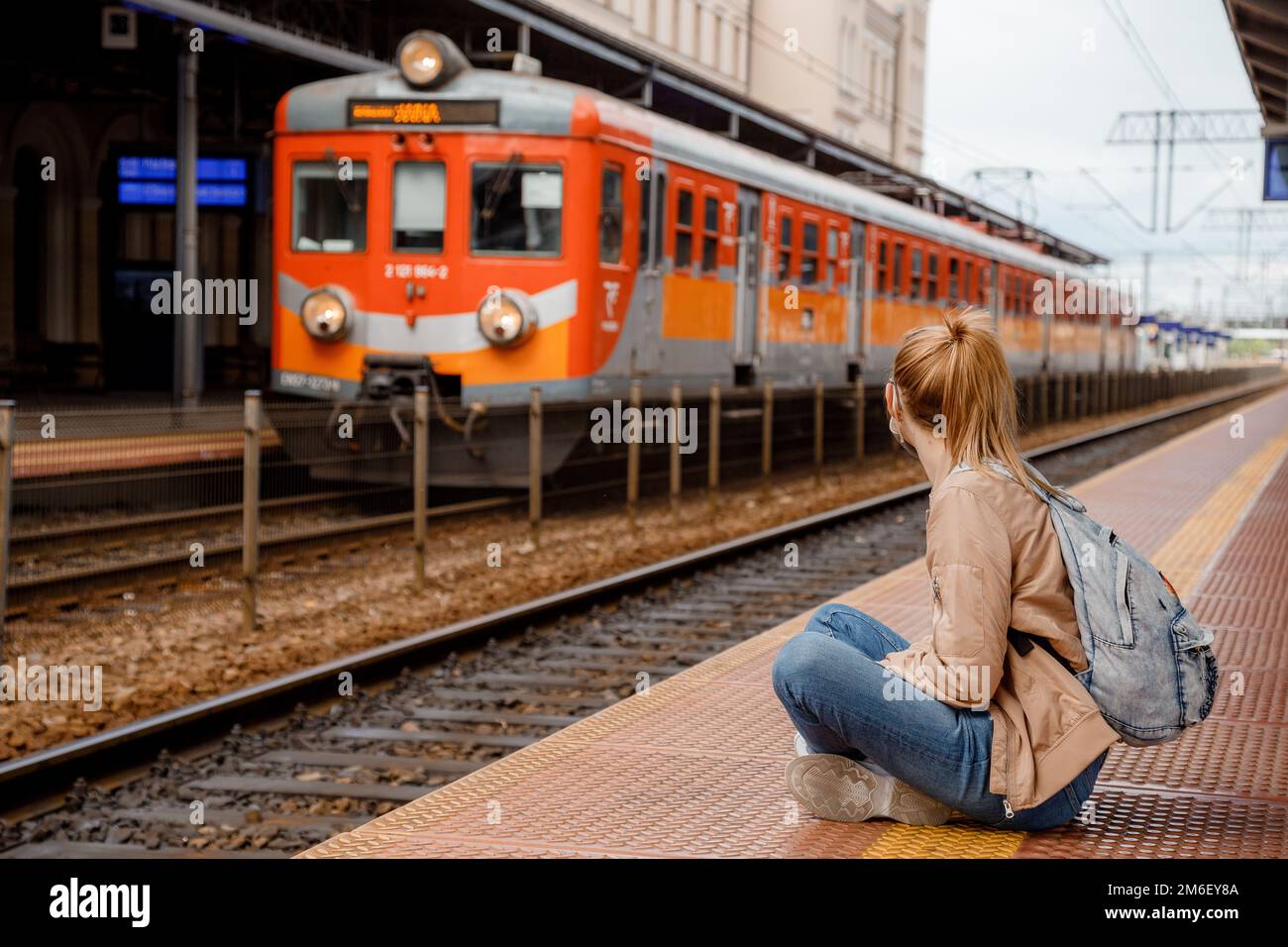 Junge Frau auf dem Bahnsteig, die auf den Zug wartet. Hübsches Mädchen am Bahnhof. Fahren Sie ...