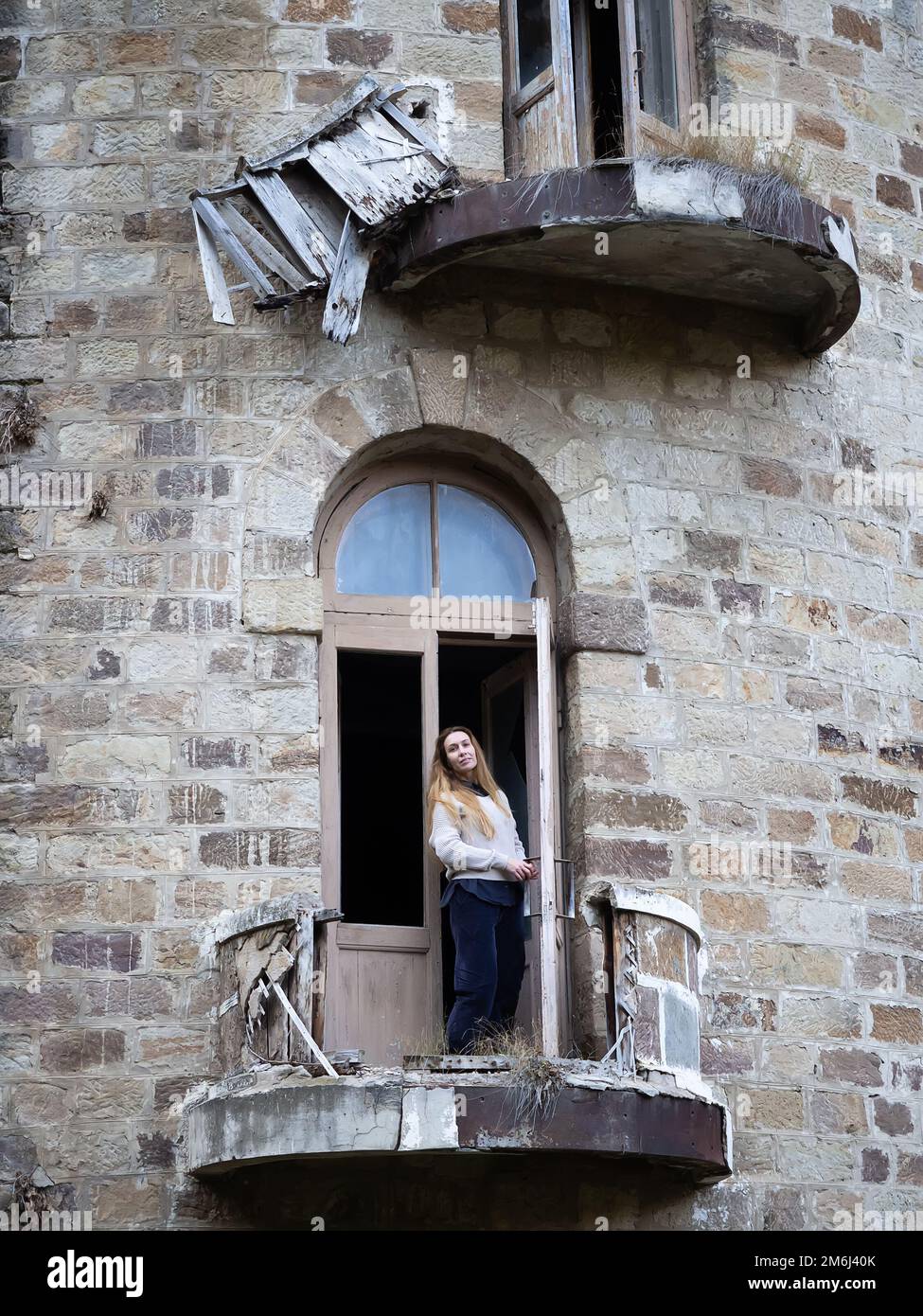 Eine Frau steht in der Tür des zerstörten Balkons eines alten ...