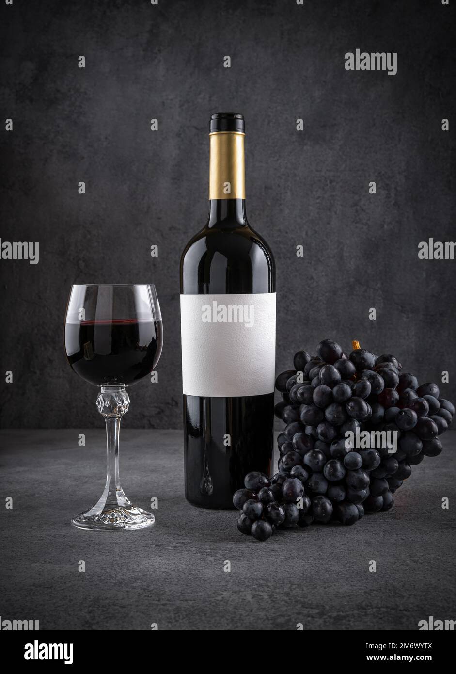 Glas und Flasche Rotwein mit Trauben auf dunklem Hintergrund. Rotwein ...