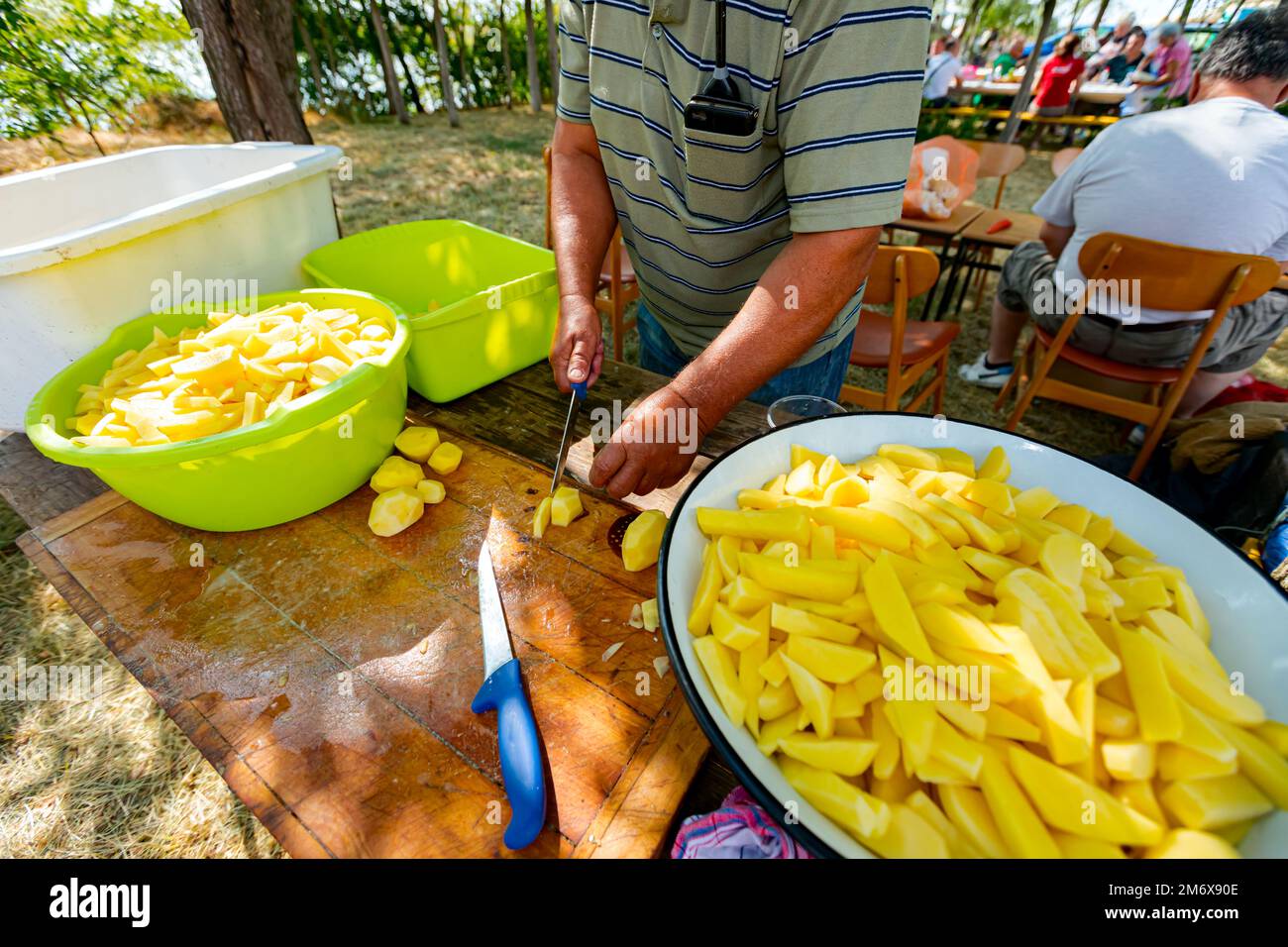 Ein älterer Bauernkocher schneidet Kartoffeln mit einem Messer in ...