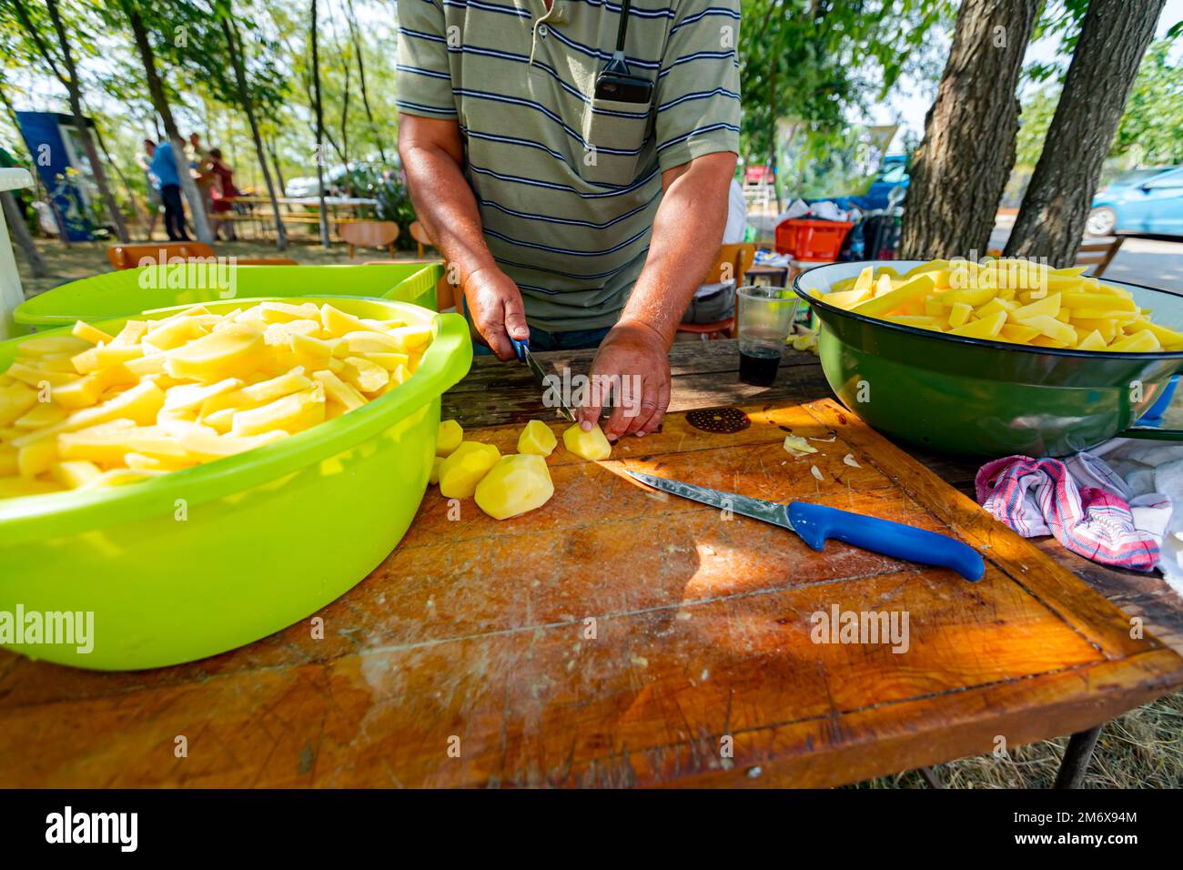 Ein älterer Bauernkocher schneidet Kartoffeln mit einem Messer in ...