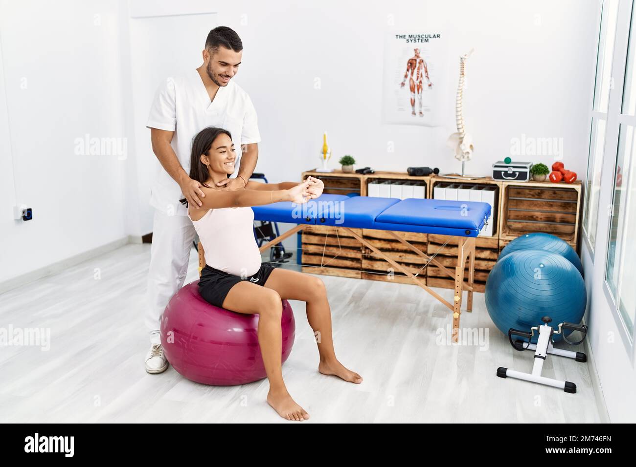 Lateinischer Mann und Frau in Physiotherapeuten-Uniform, die eine Reha-Sitzung mit einem FIT ...