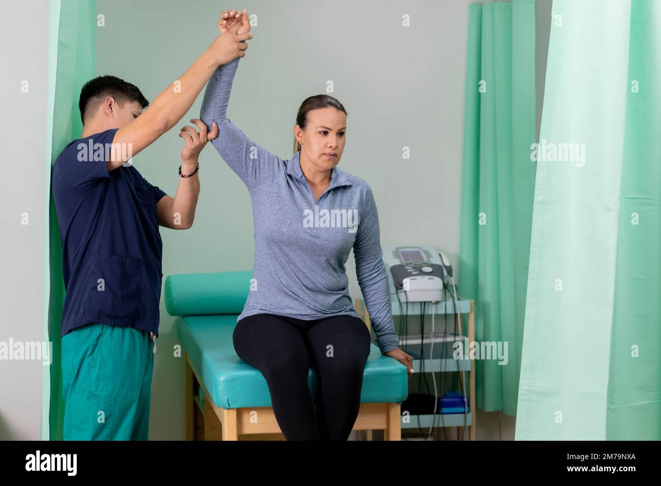 Arzthelferin hebt den Arm einer Frau, die in der Klinik auf dem Tisch ...