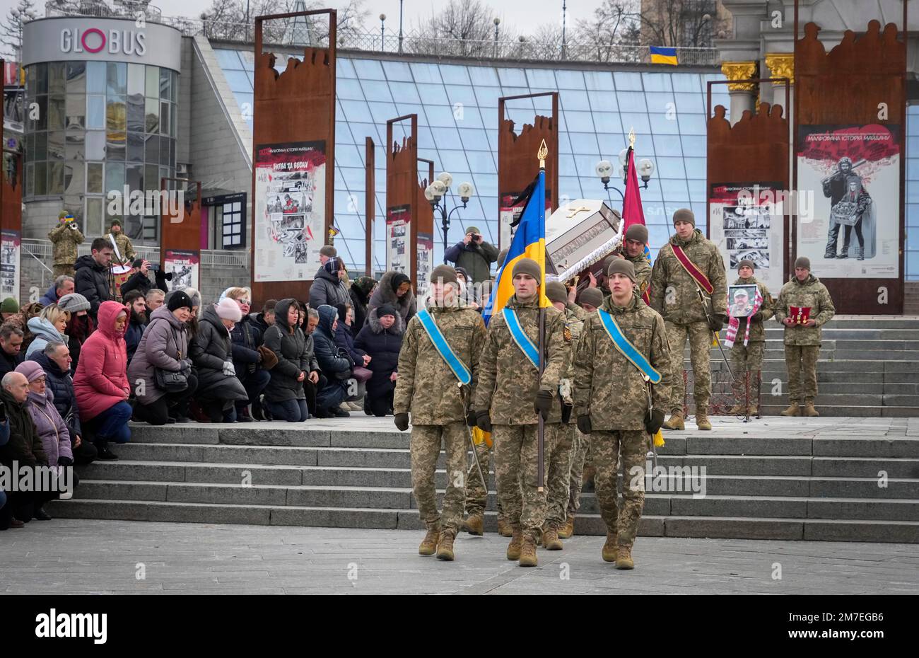 People kneel as the Ukrainian servicemen carry the coffin of their ...