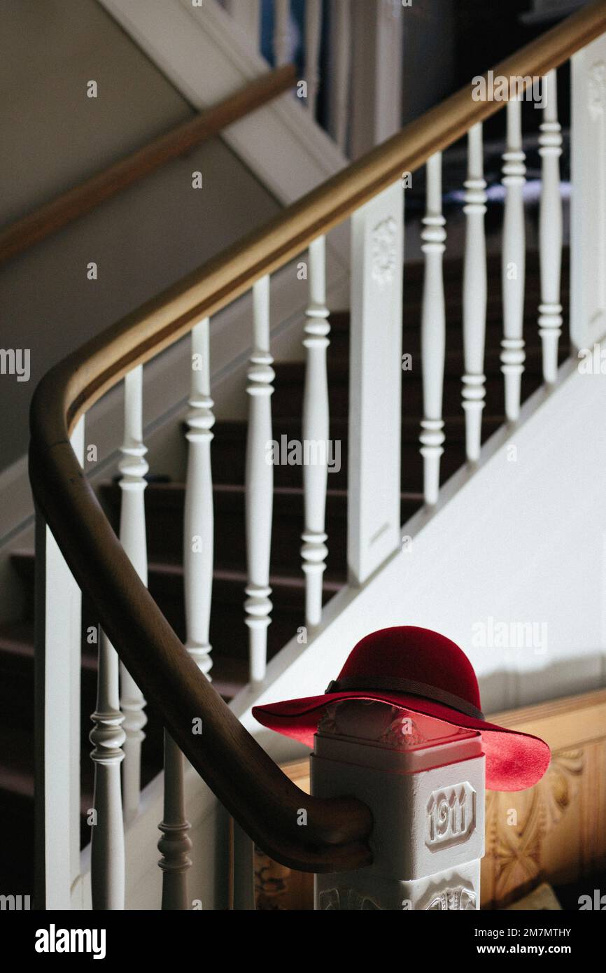 Roter Hut auf dem Geländer einer Treppe in einer alten Villa ...