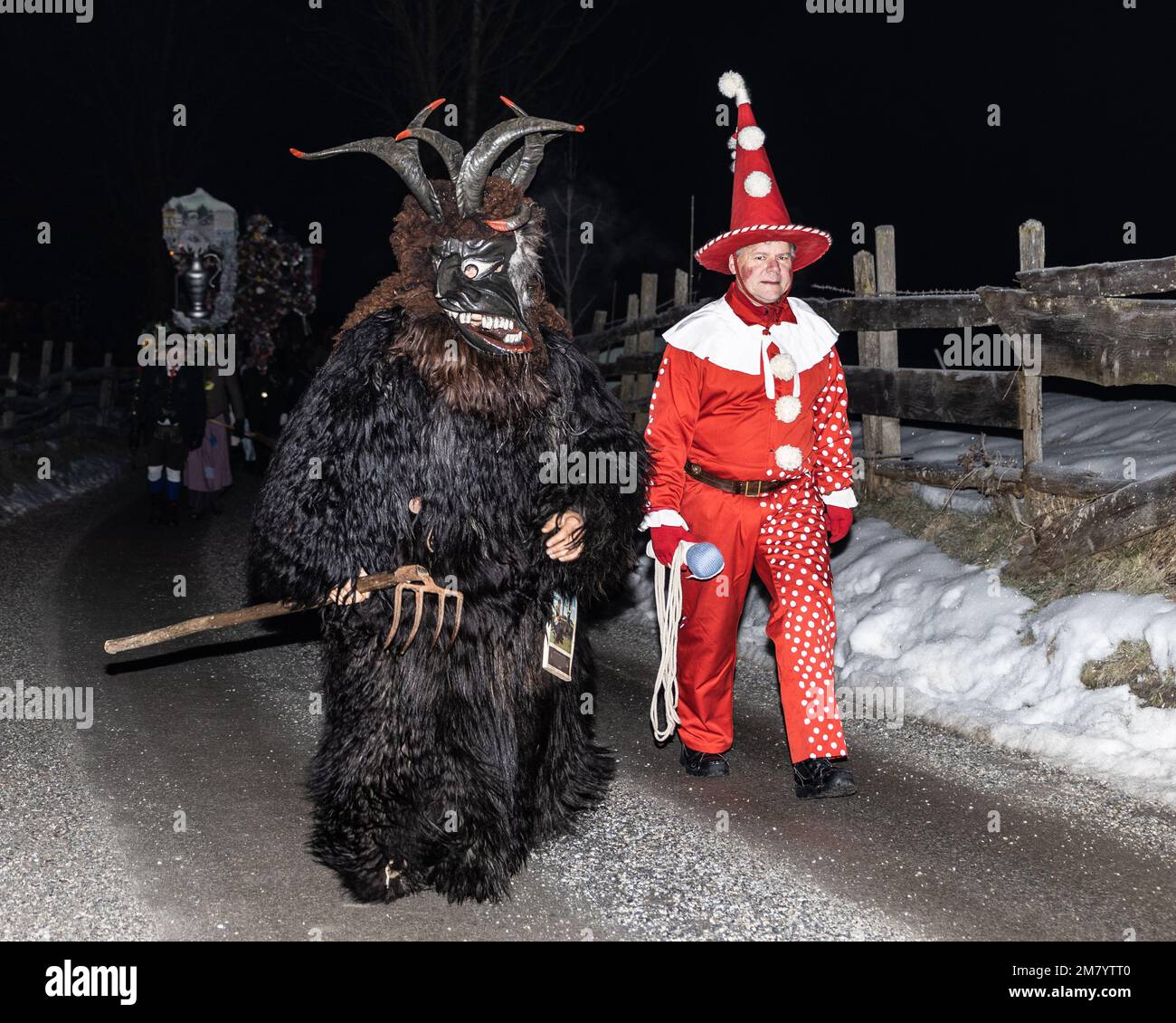 Ein Clown und ein krampus mit Heugabel in einer perchten-Prozession ...