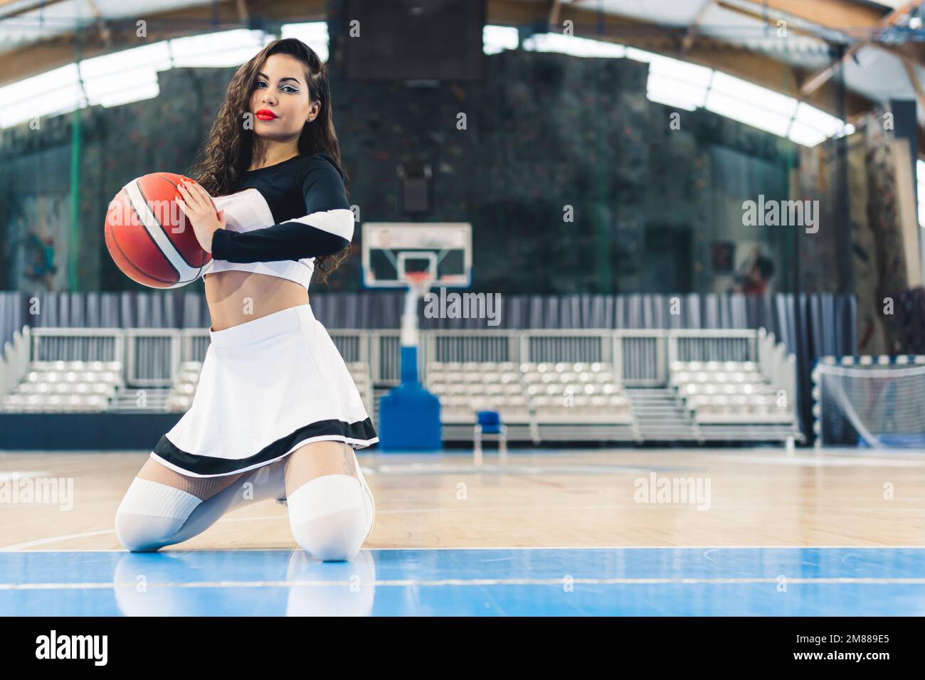 Eine Junge Athletische Cheerleaderin Die Auf Einem Basketballfeld Auf Den Knien Sitzt Sie