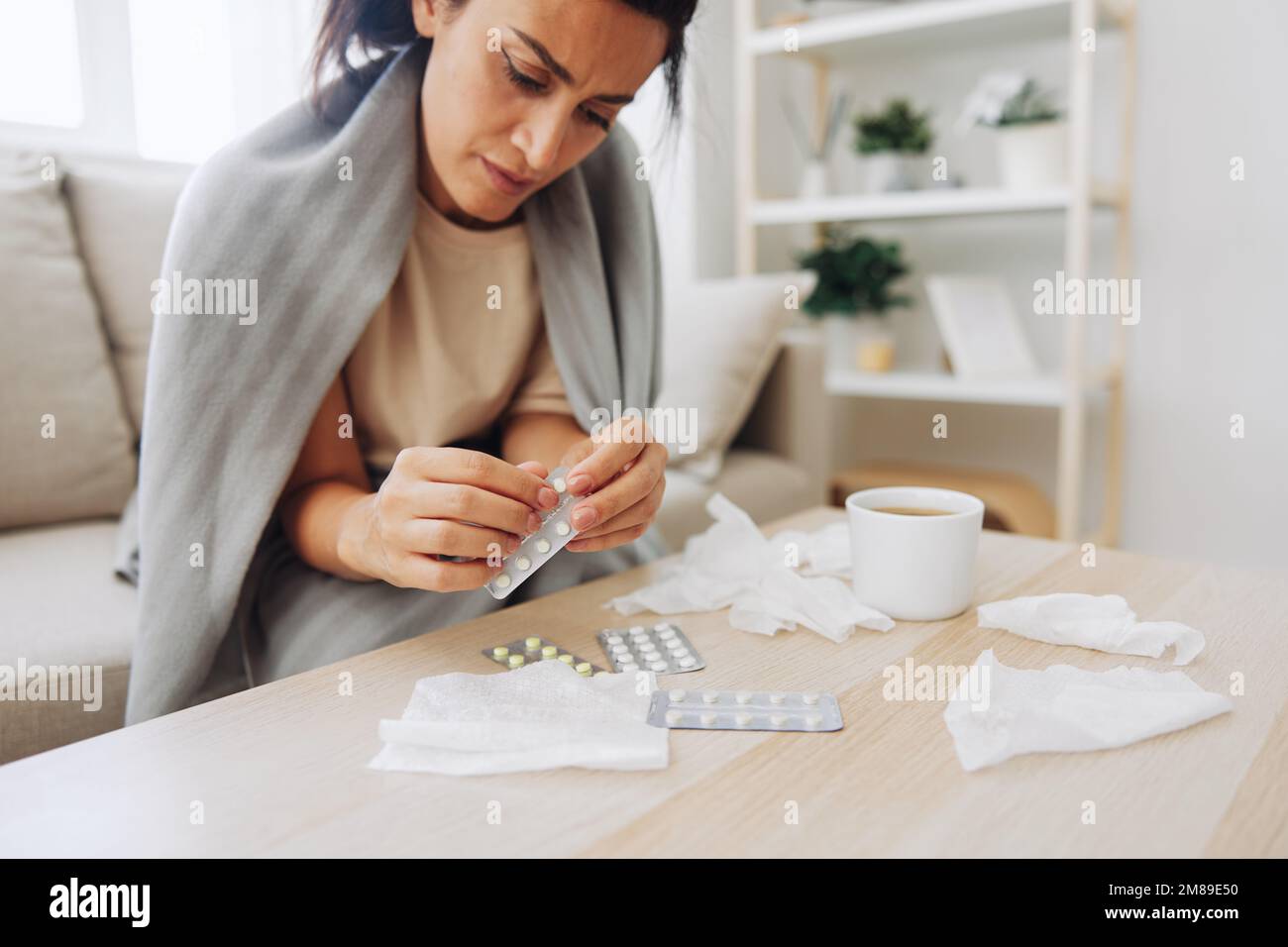 Eine Frau mit einer Erkältung mit Pillen wird zu Hause behandelt wählt ...
