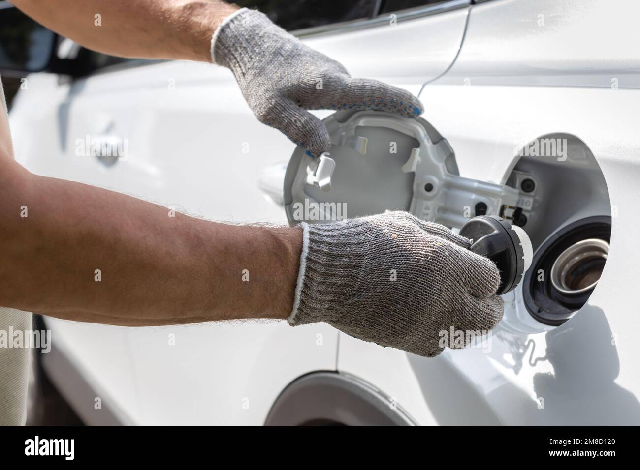 Mann öffnet die Luke des Benzintanks des Autos. Der Tanker öffnet den ...