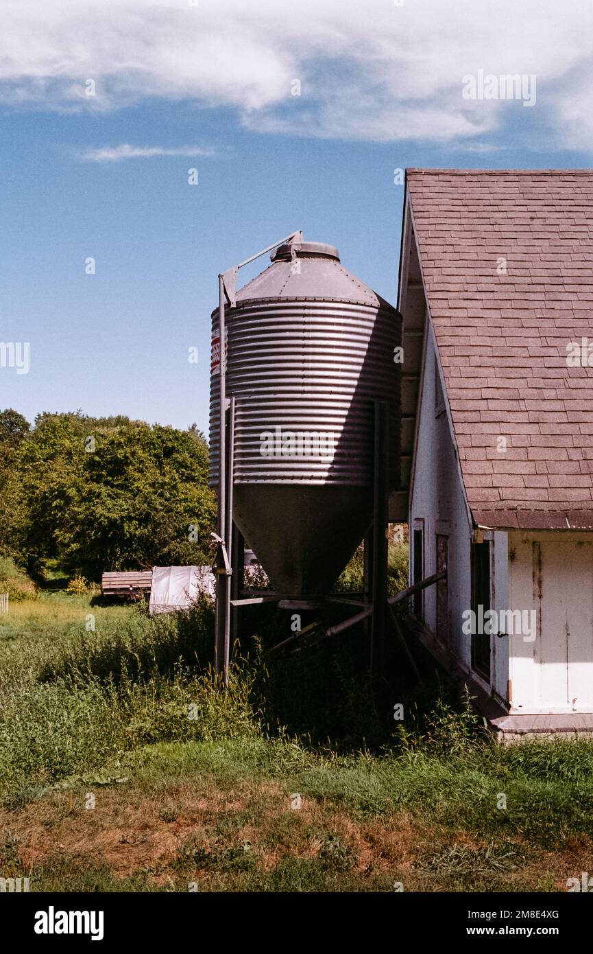 Ein Silo aus Metallkorn hinter einem weißen Hühnerstall an einem ...