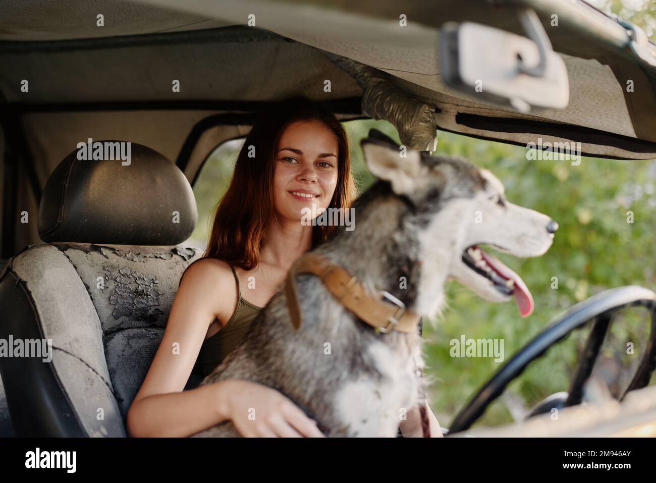 Frau und ihr Husky-Hund sind glücklich im Auto unterwegs Lächeln mit ...