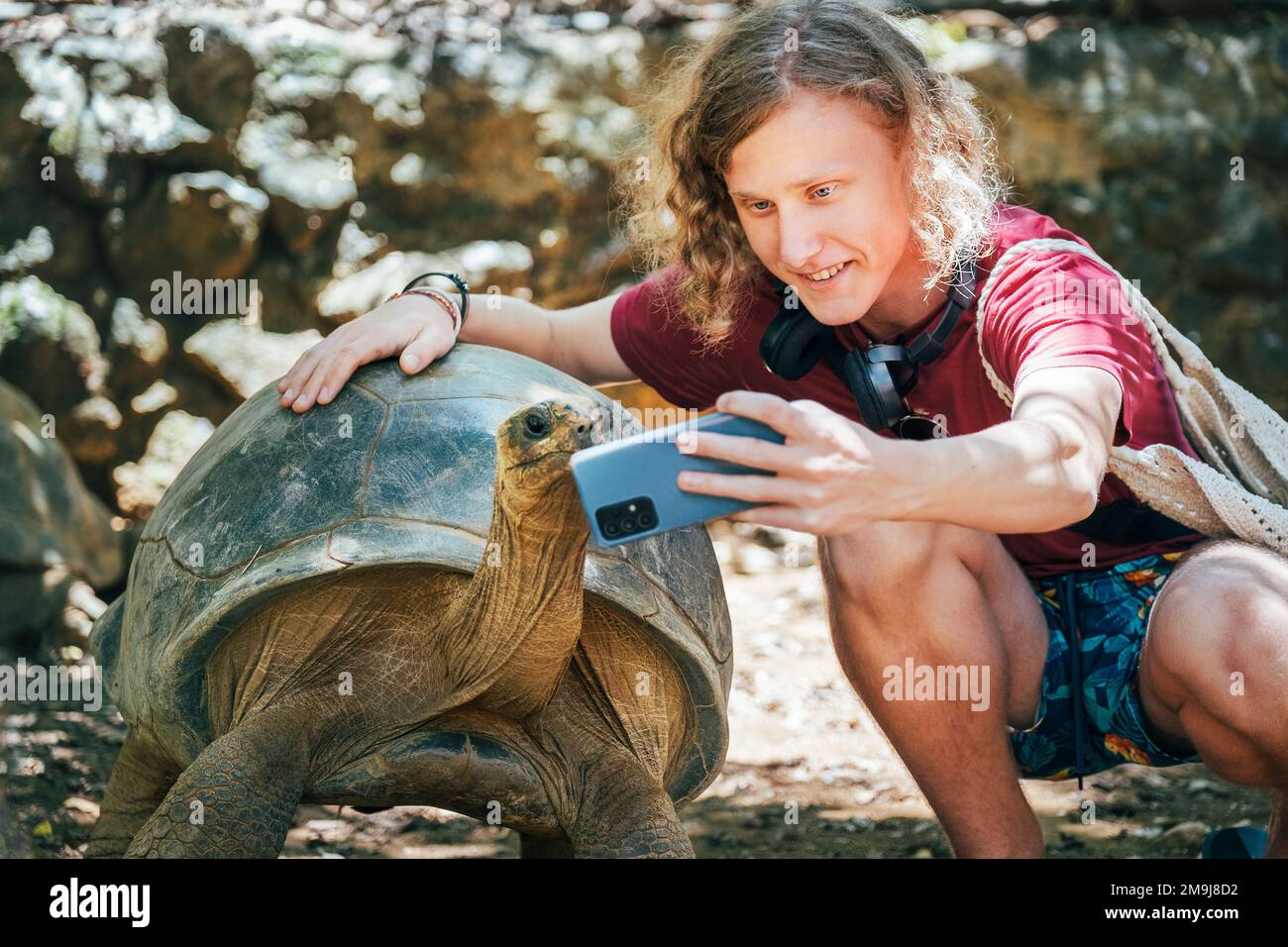Lächelnder Touristenjunge, der mit dem Handy ein Selfie mit Aldabra ...