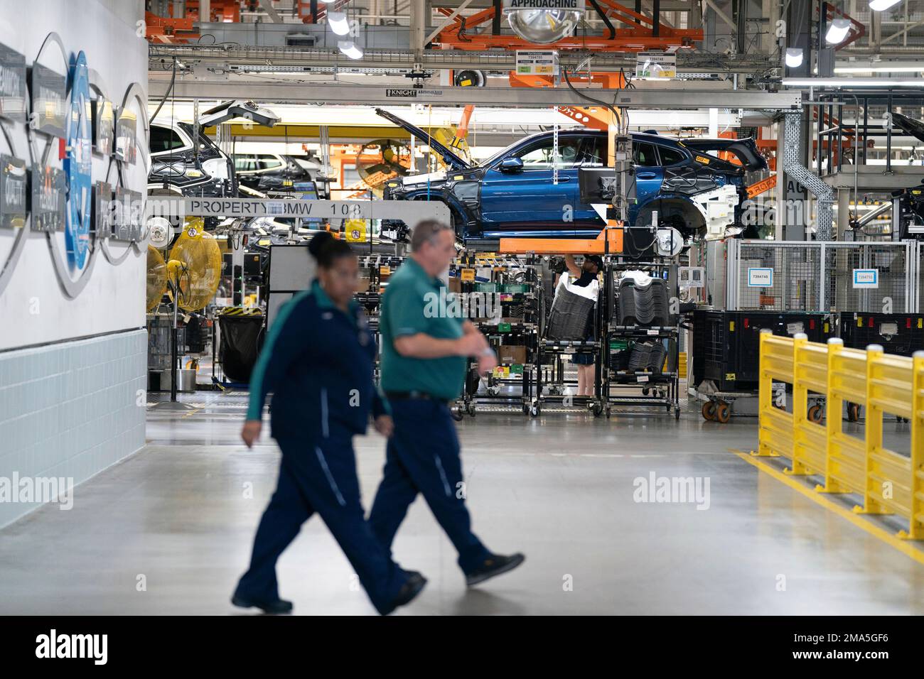 People walk past part of the assembly line at the BMW Spartanburg plant ...