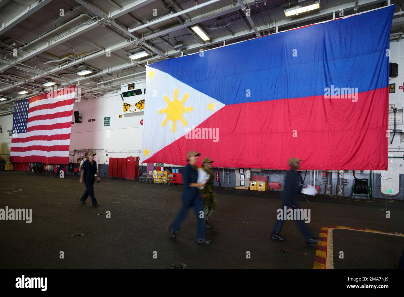 US Navy sailors walks beside the Philippine and US flag inside the US ...