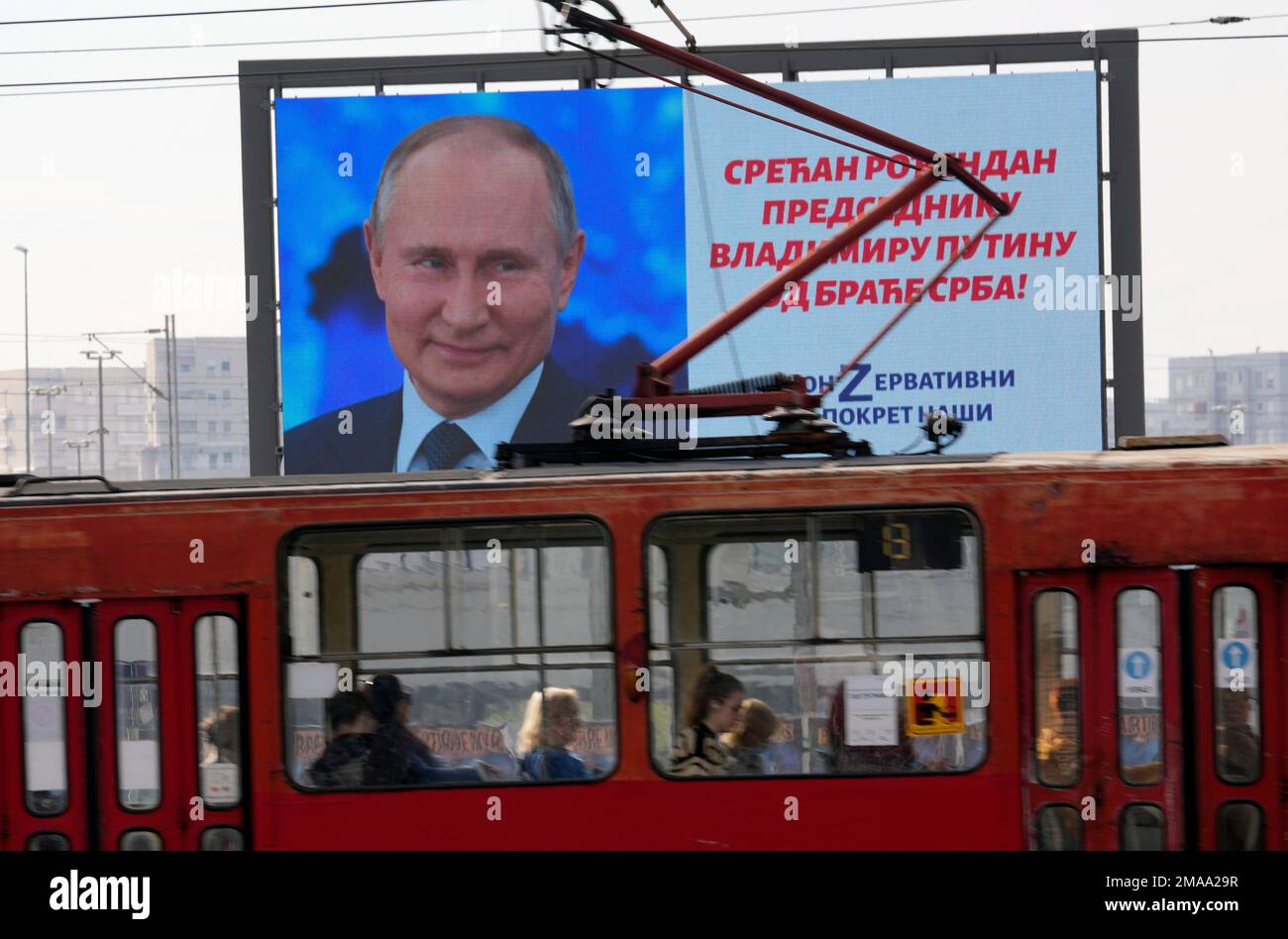 People look through the tram windows as they pass a big screen showing ...