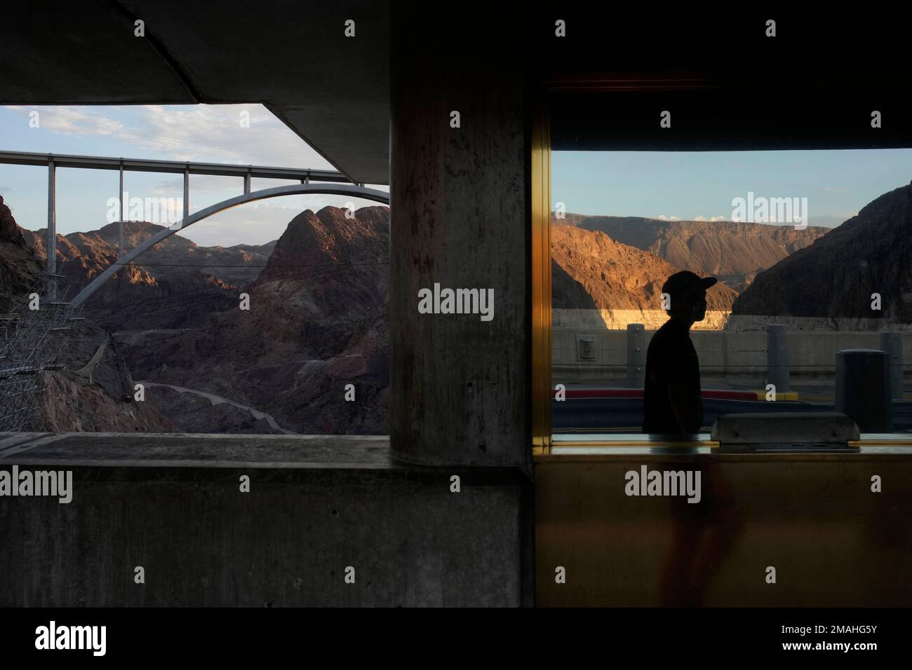 FILE - A person is reflected in a window as they walk across Hoover Dam ...