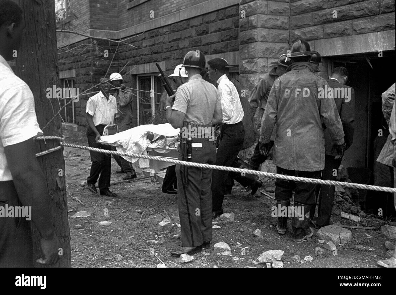 FILE - Firemen and ambulance attendants remove a covered body from ...