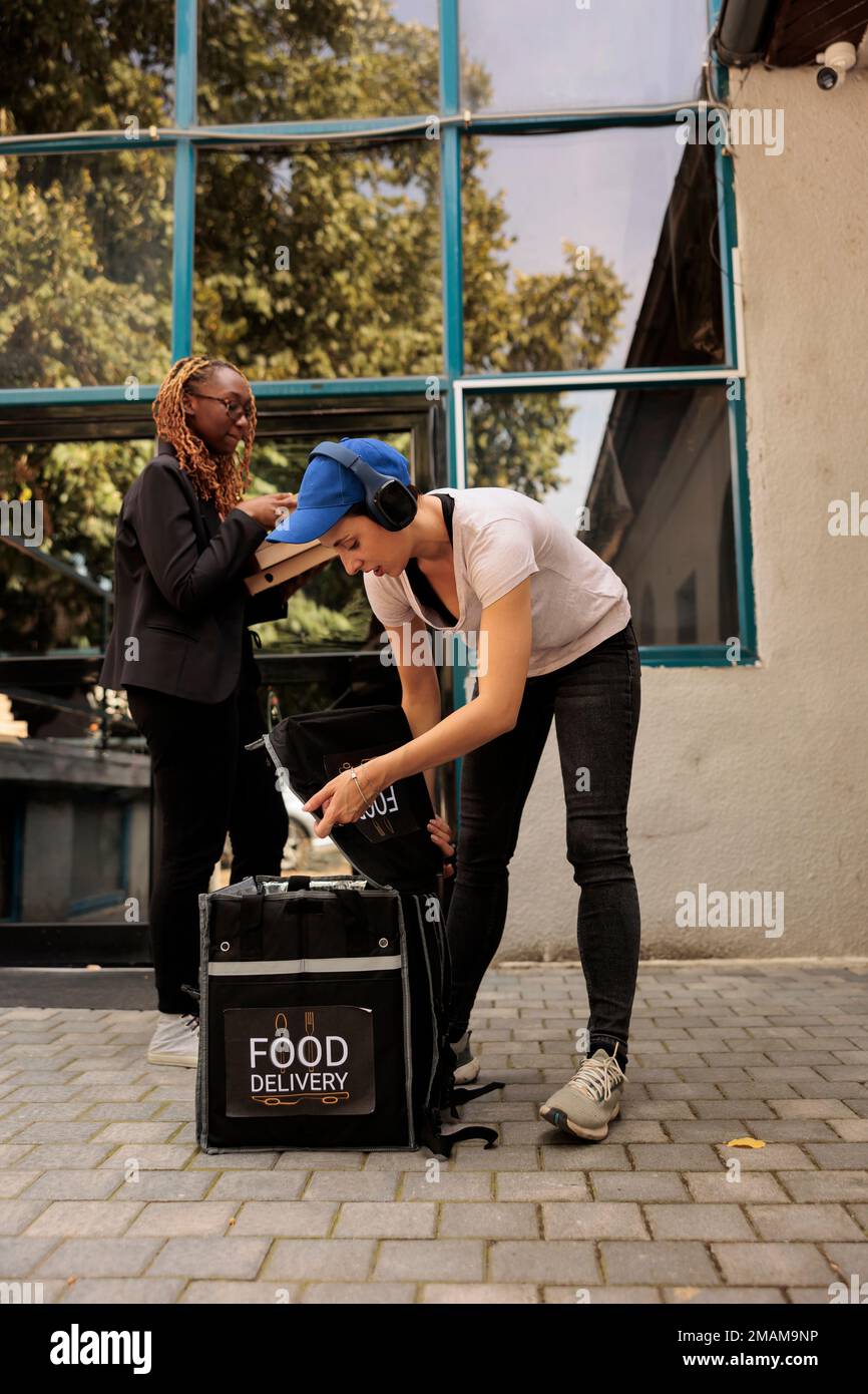 Mitarbeiter im Food Delivery Service mit Kopfhörern, die ...