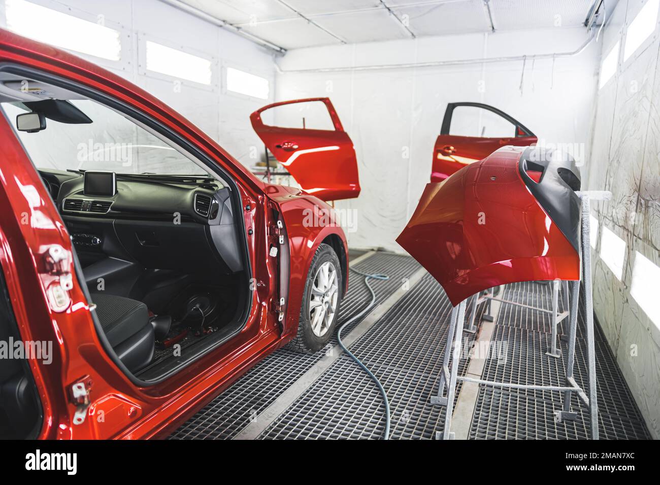 Ein luxuriöses rotes Auto in einer Lackiererei, dessen Türen für einen ...
