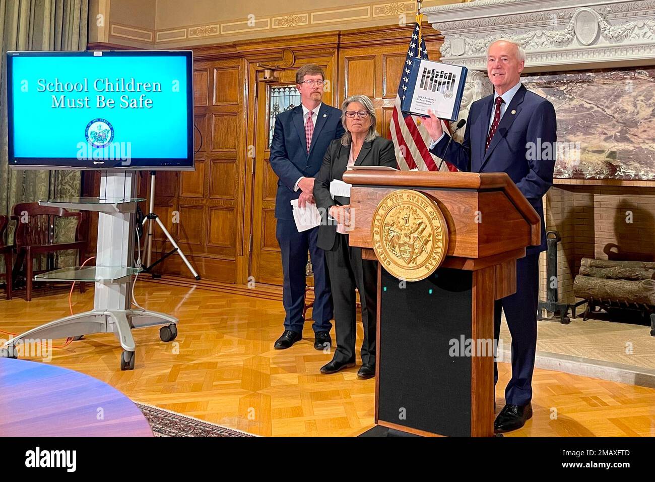 Arkansas Gov. Asa Hutchinson holds up an interim report from a ...