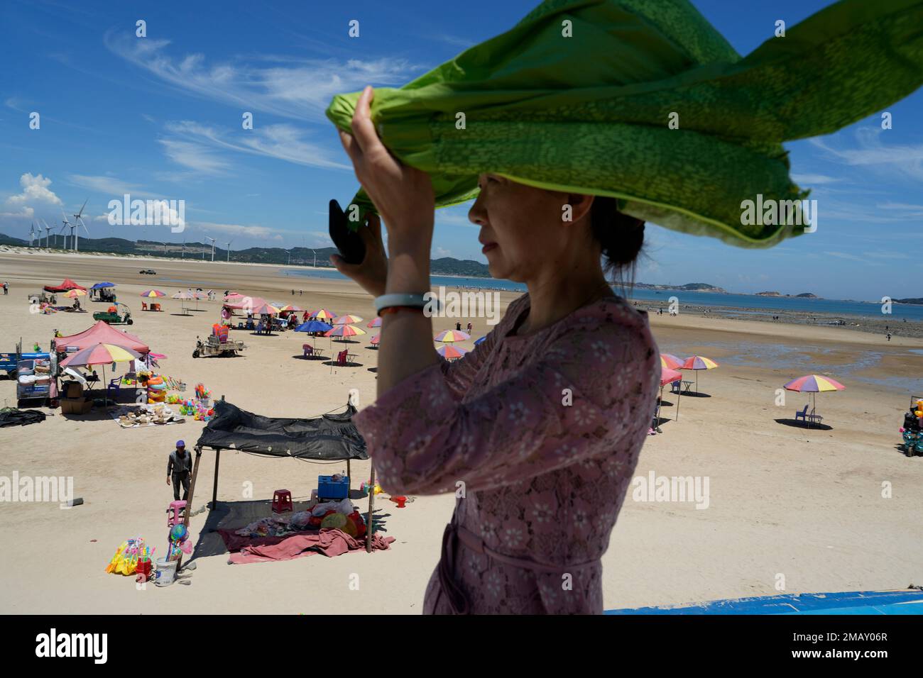 A tourist covers up from the sun and wind as she visits a beach along ...