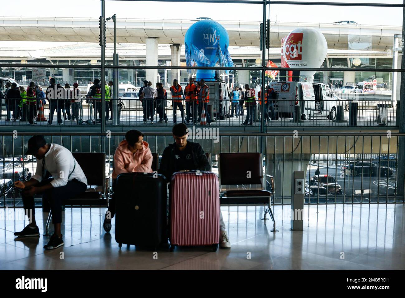 Passengers wait at Charles de Gaulle airport while strikers gather outside the terminal Friday ...