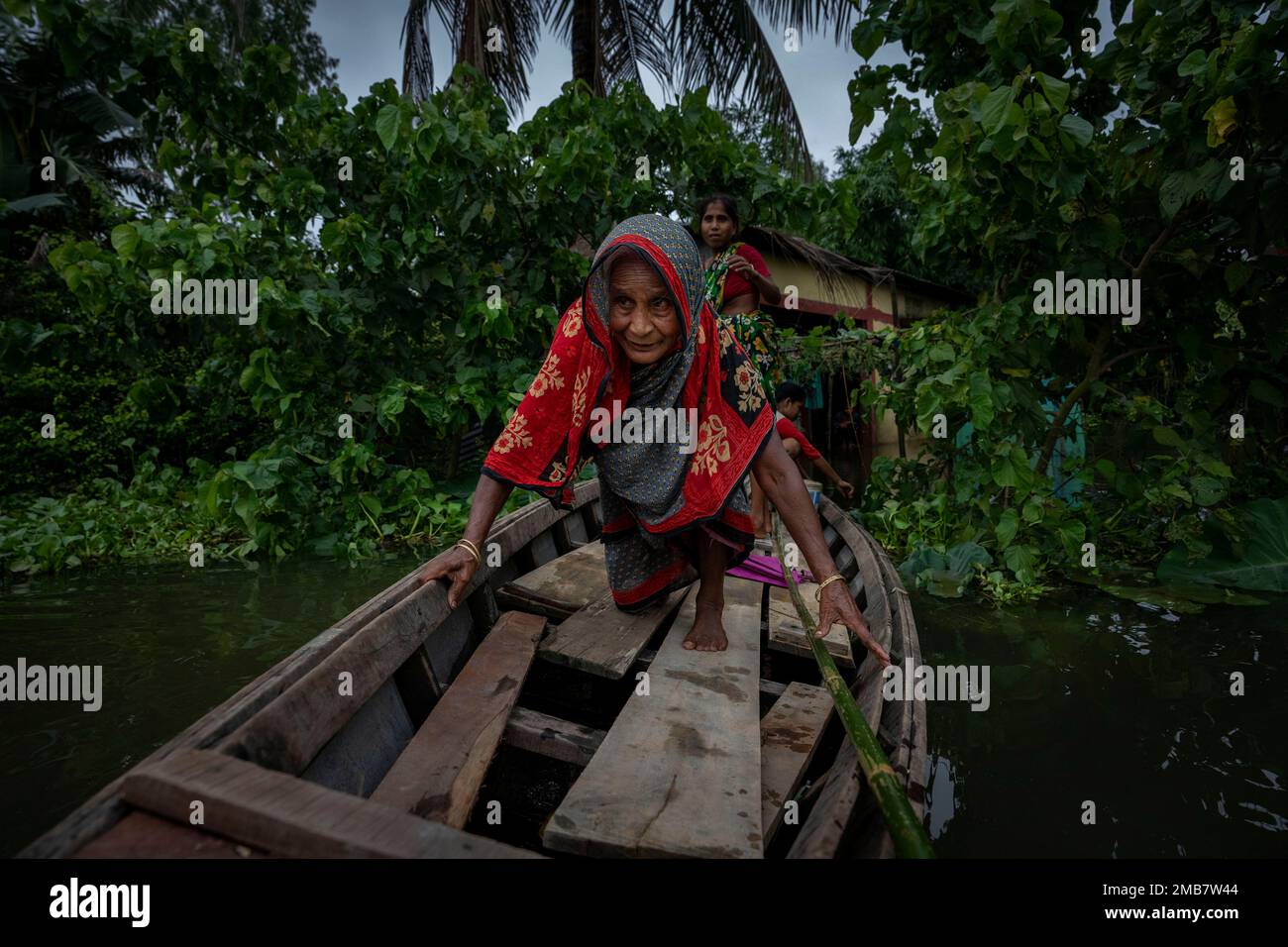 An elderly flood affected woman climbs on a boat to reach on higher ...