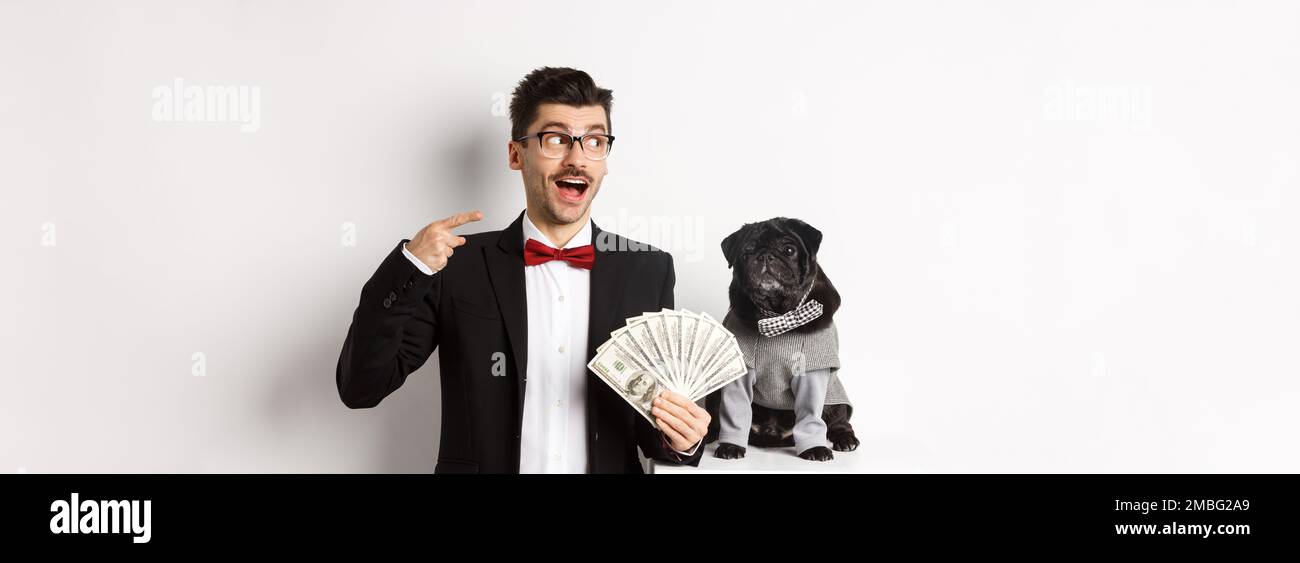 Glücklicher junger Mann im Anzug verdient Geld mit seinem Hund. Kerl ...