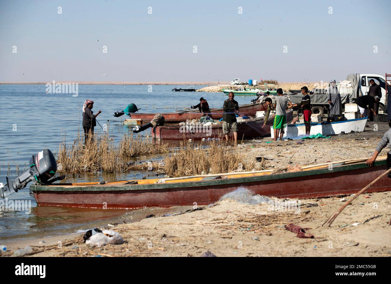 Fishermen stand on the bank of Razzaza Lake, also known as Lake Milh ...