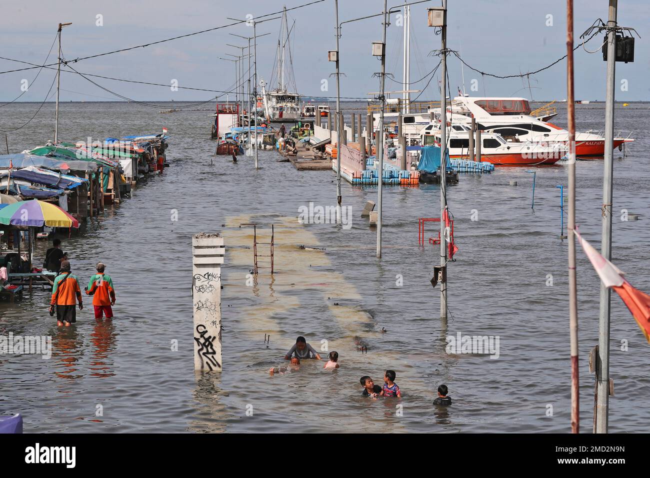 Children play in the water during a tidal flood at the Muara Angke Port ...