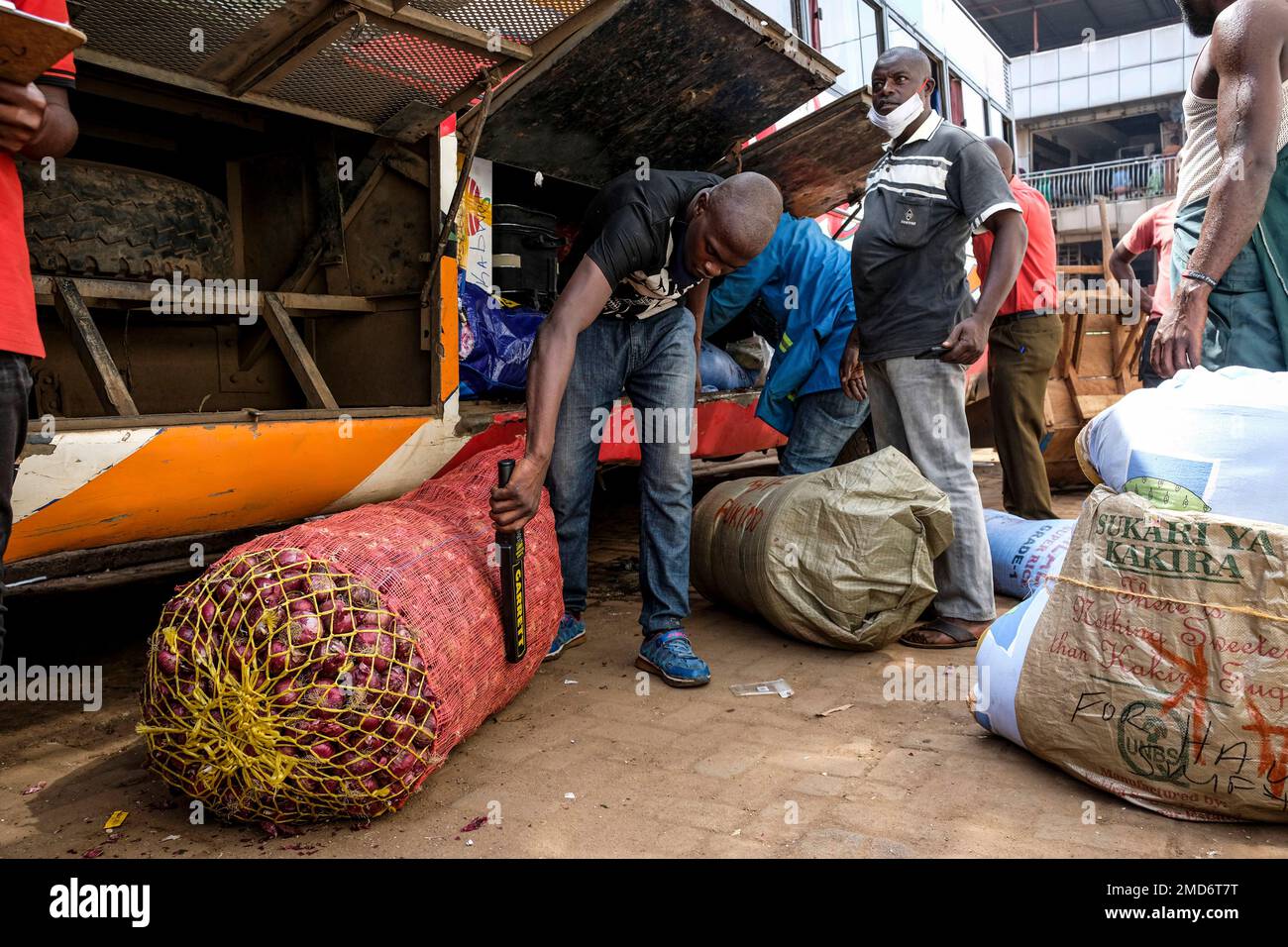 A bus security officer checks a bundle of red onions using a metal ...