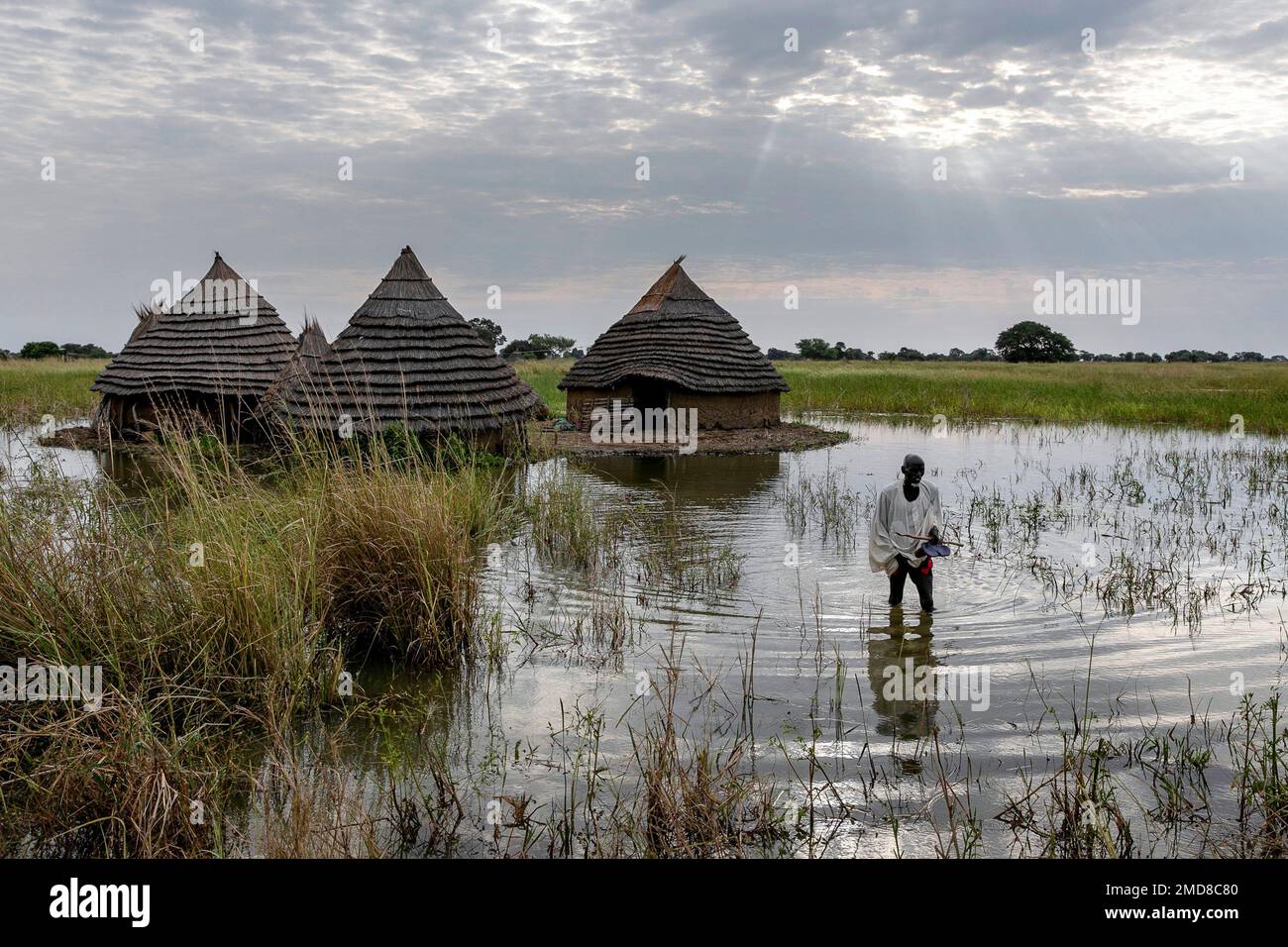 Yel Aguer Deng, who does not know his age, walks through water from his ...