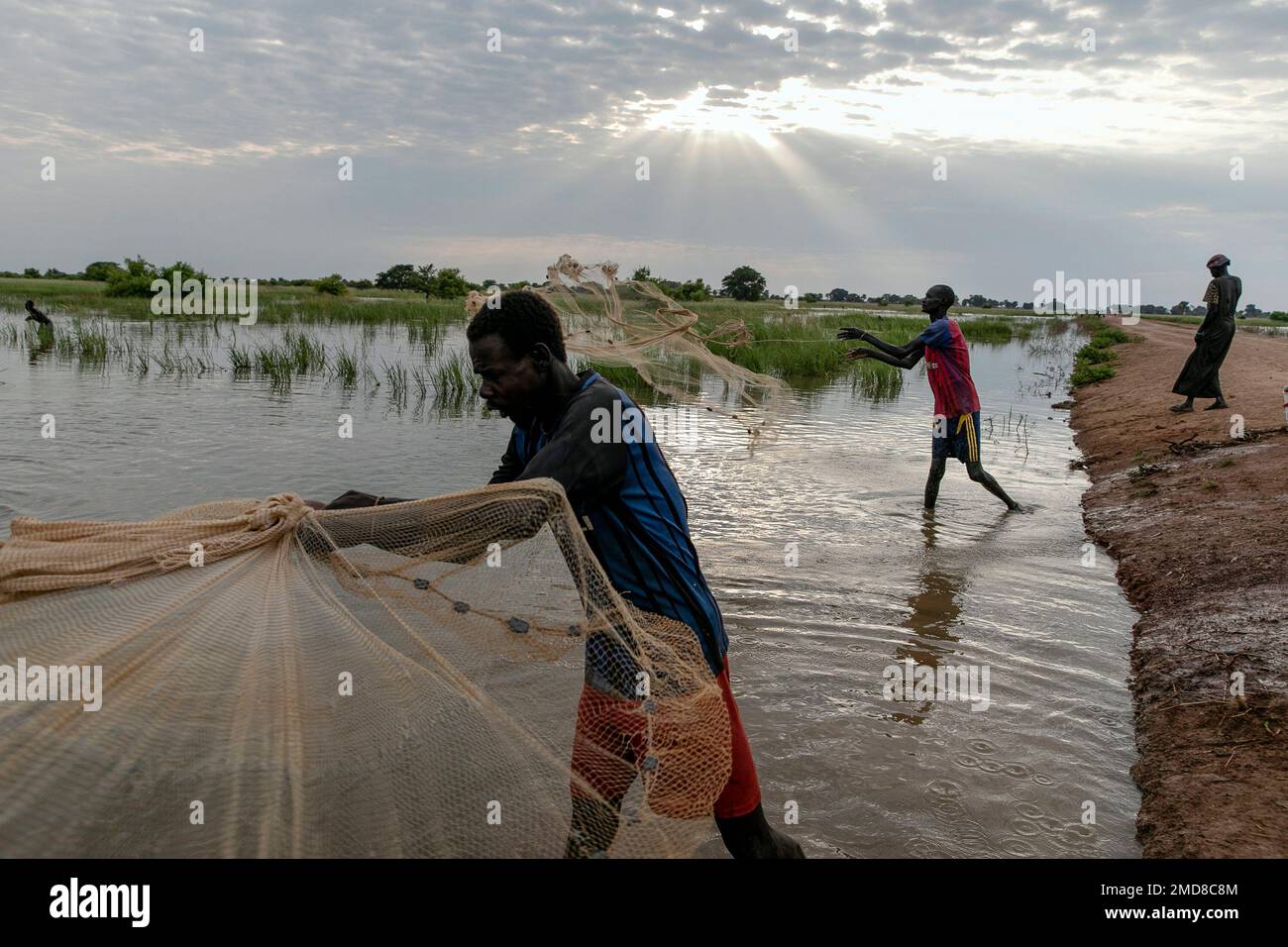Daniel Deng, center, a 50-years-old father of seven, casts his fishing ...