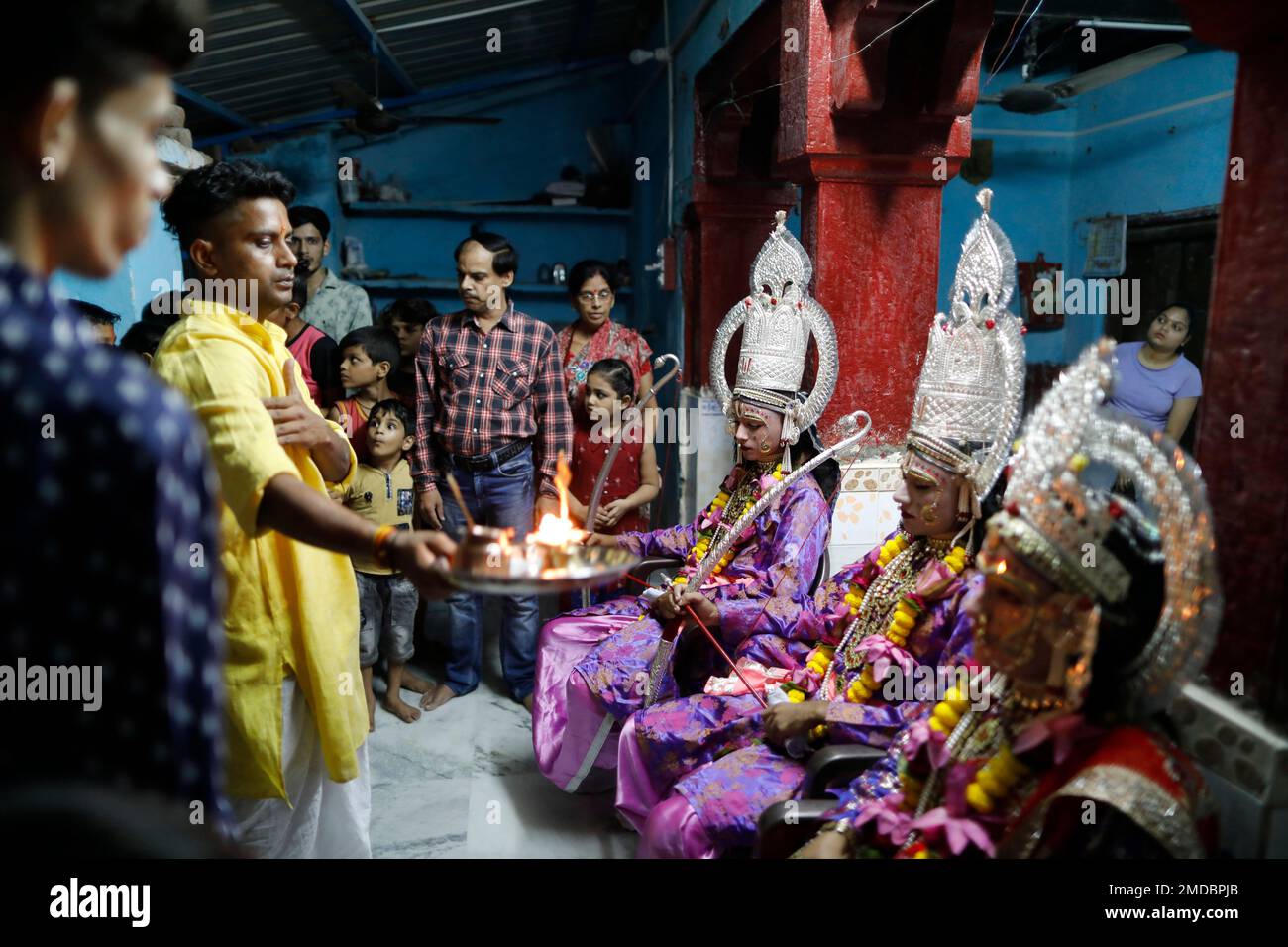 A Hindu devotee holds a traditional oil lamp as he offers prayers to ...