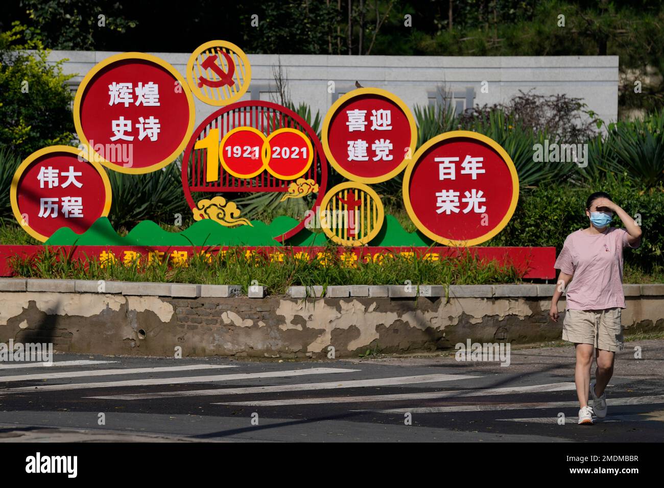 A woman walks past propaganda promoting the centennial of the founding ...