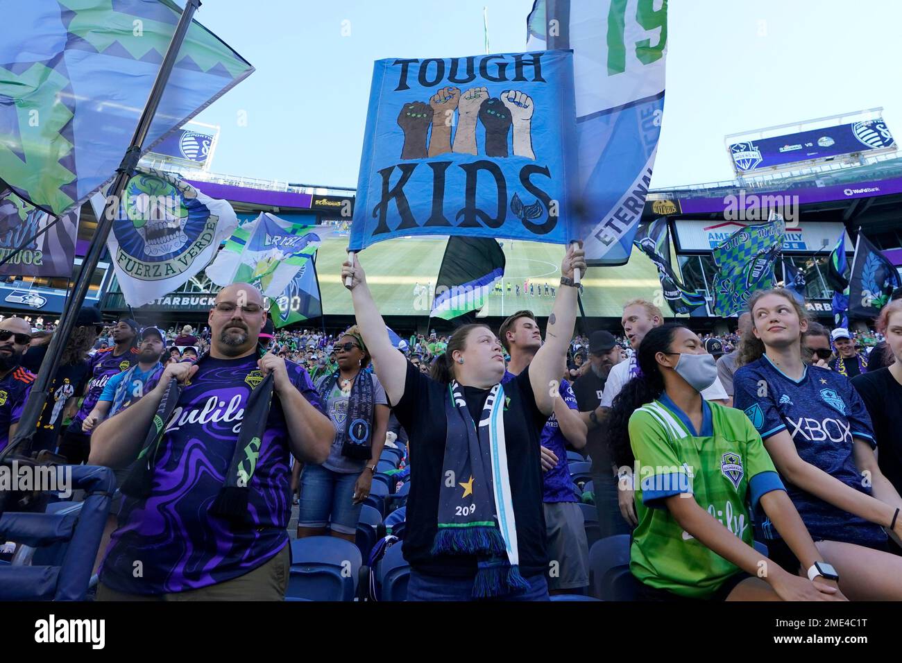 Members of the Emerald City Supporters and other fans wave flags ...