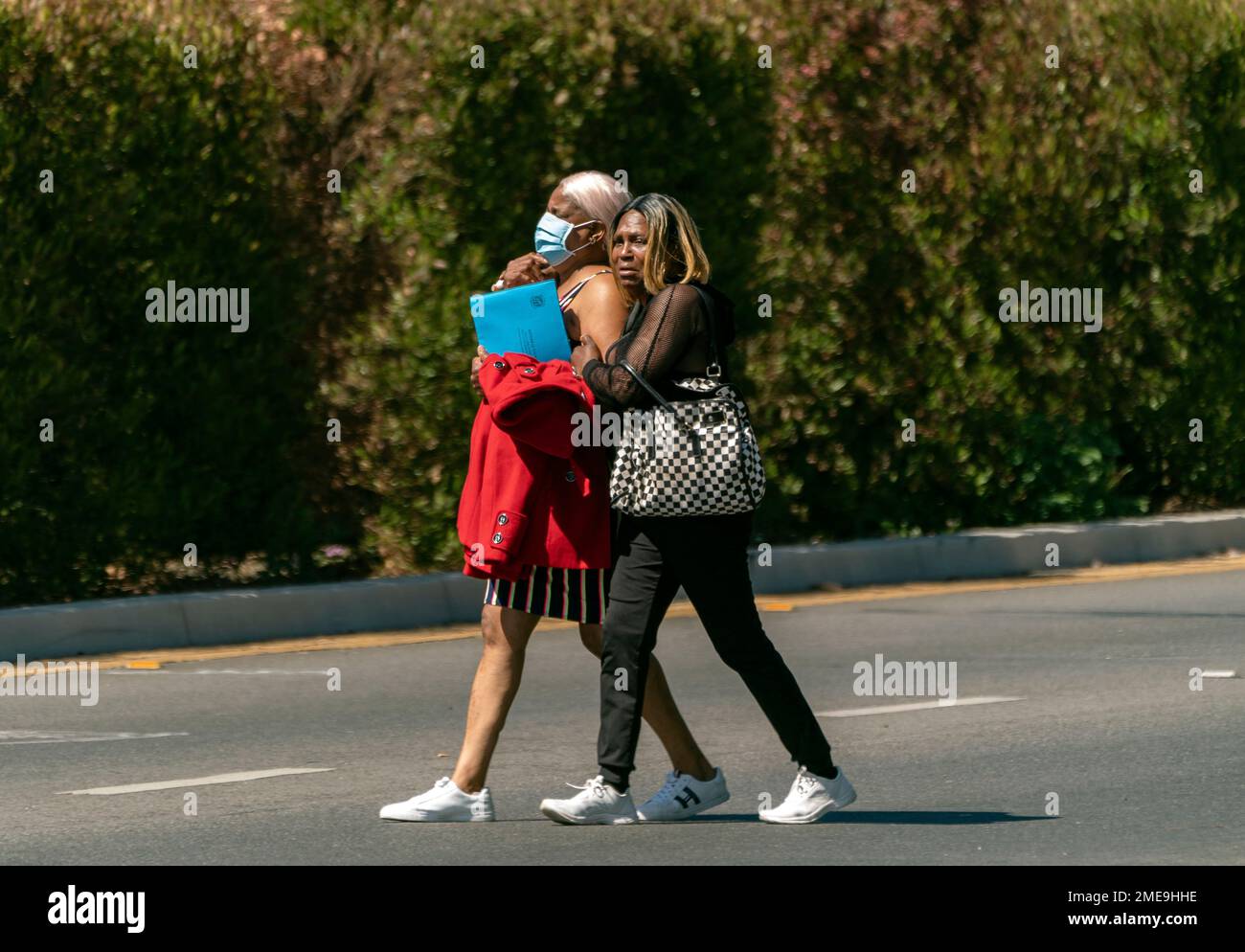 Two unidentified women hug after running behind a departing Los Angeles ...